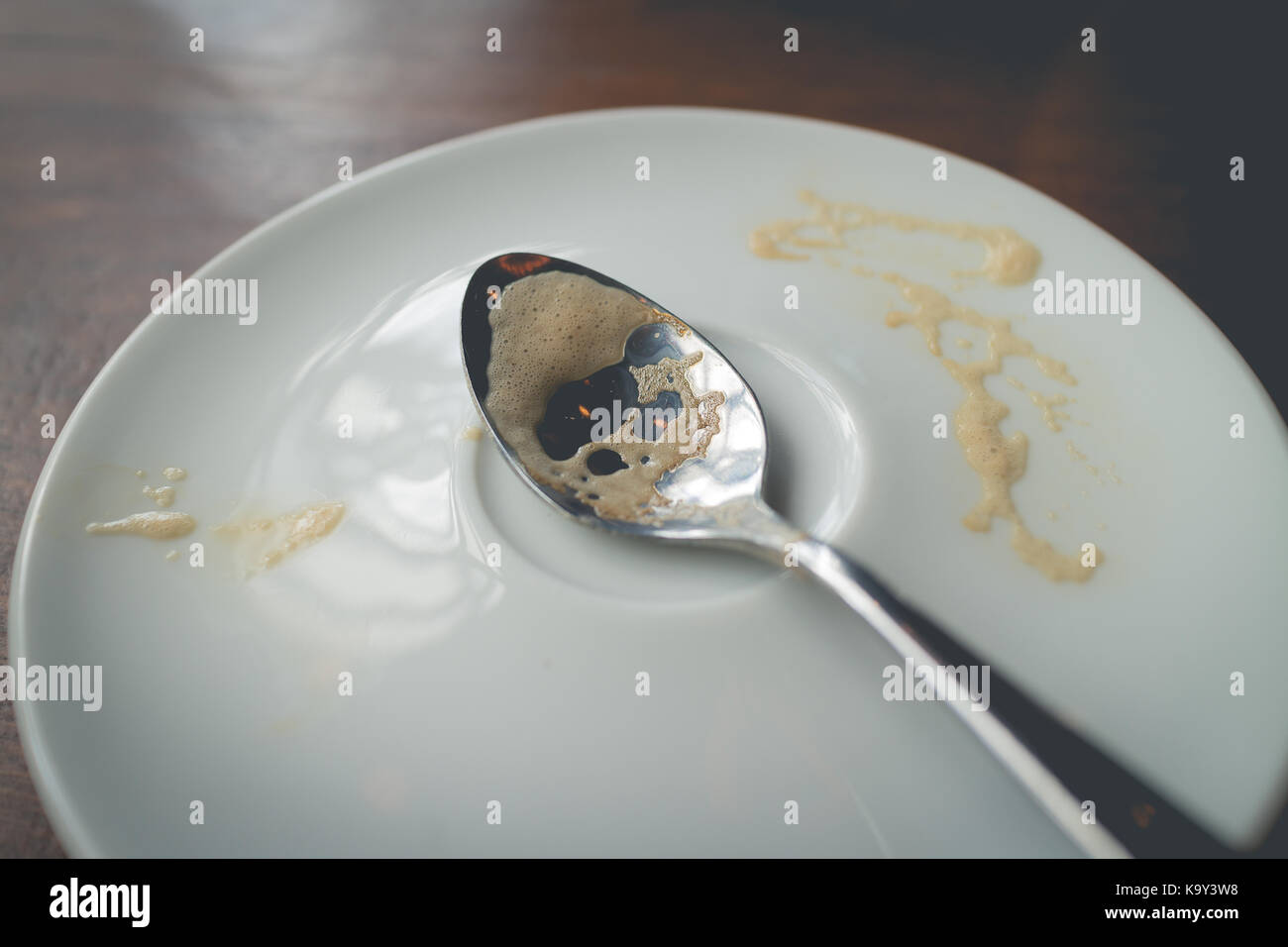 Coffee stain on metal spoon and white ceramic dish.(Filtered image ...