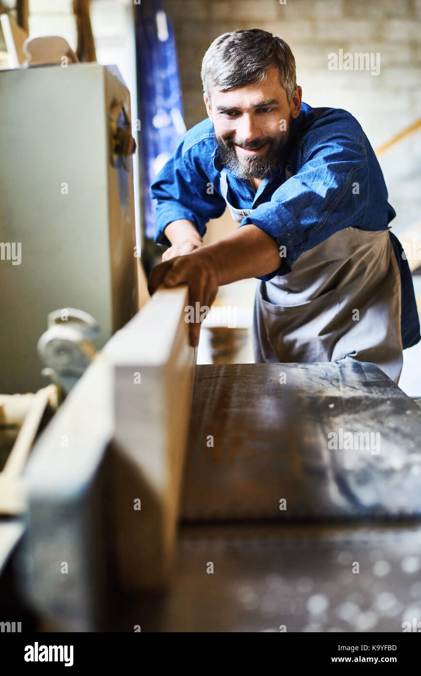 Portrait of skilled bearded carpenter smiling happily while working ...
