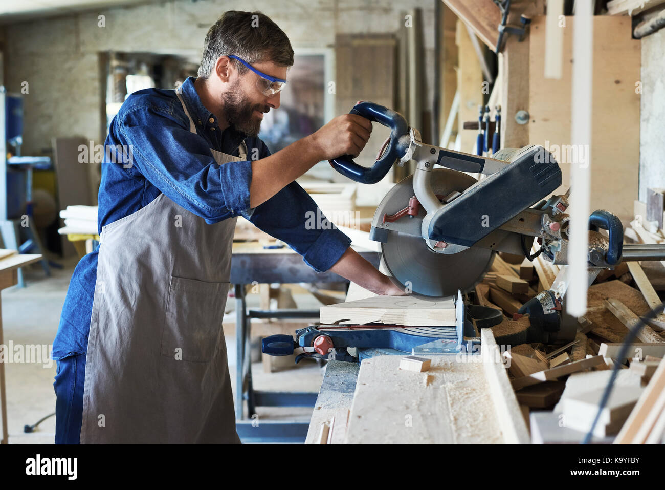 Side view portrait of bearded carpenter cutting wood using sawing ...