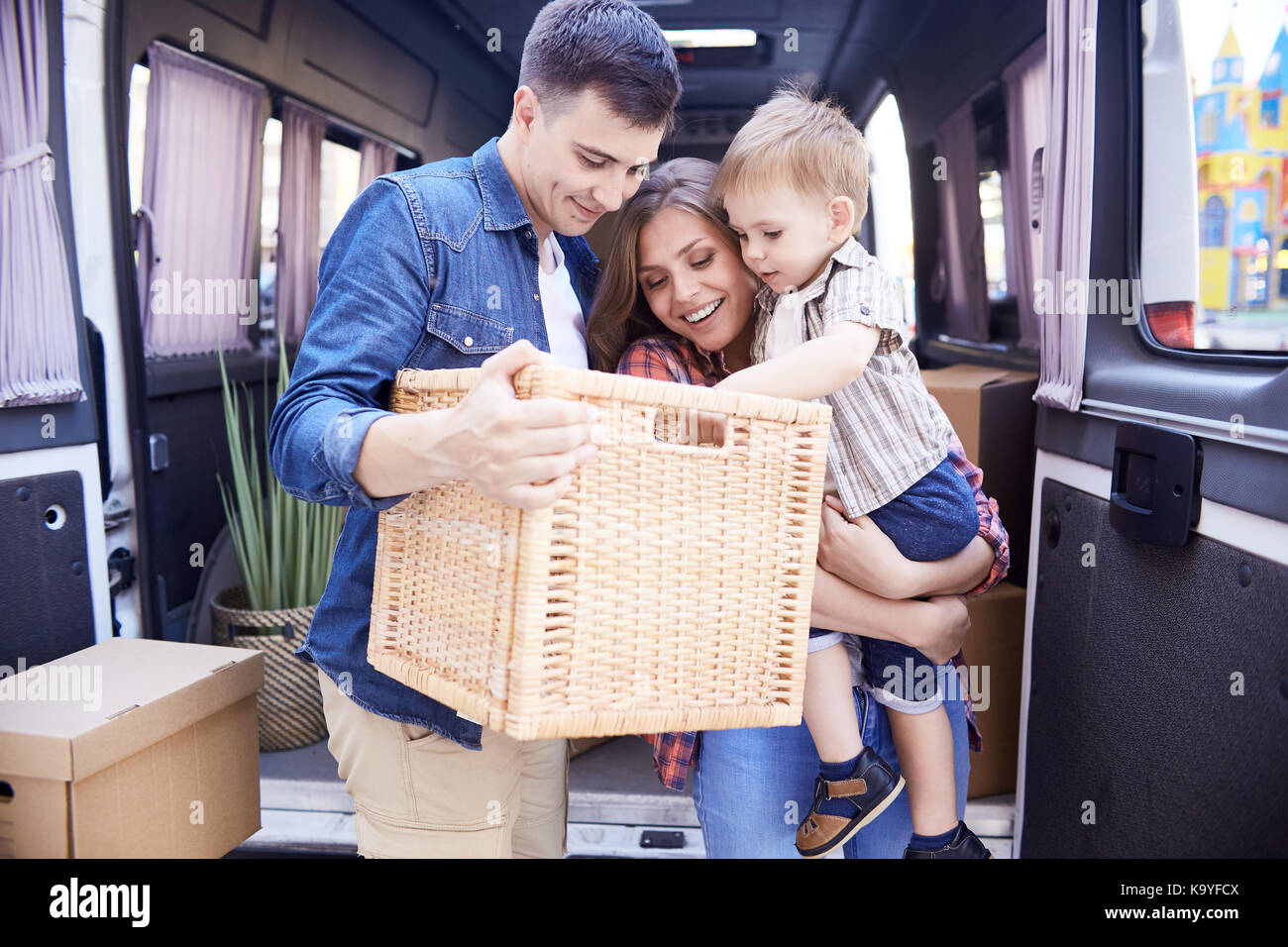 Portrait of happy young family with little boy unloading moving van ...