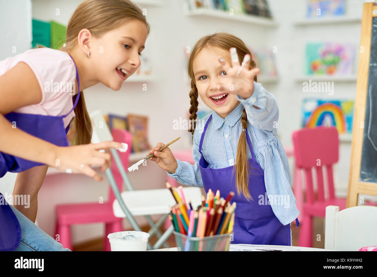 Portrait of two little girls enjoying art and craft lesson in ...