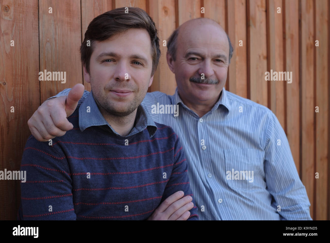 Father and son stand together near wooden background Stock Photo - Alamy