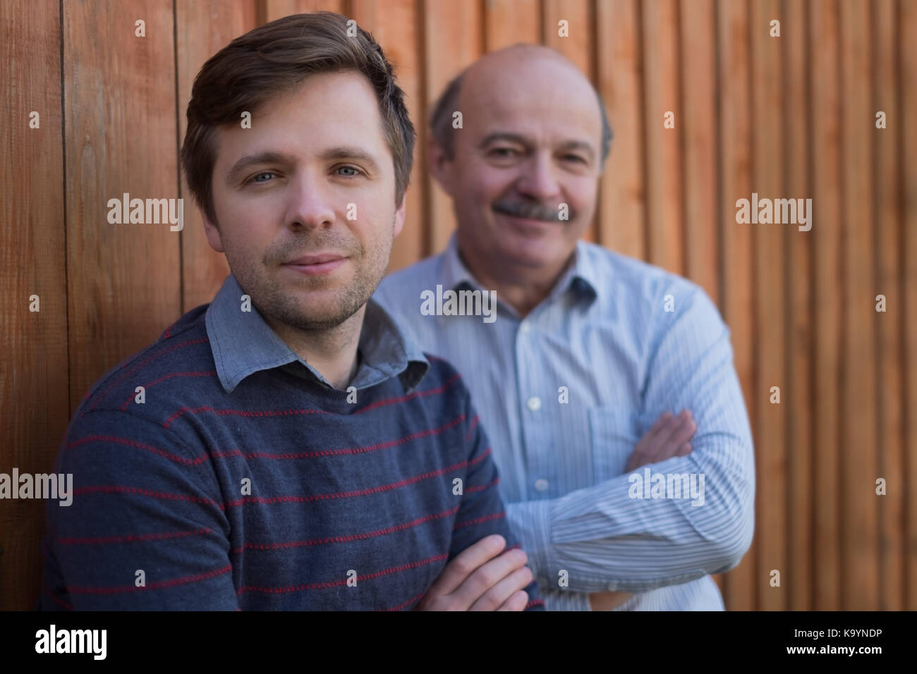 Father and son stand together near wooden background Stock Photo - Alamy