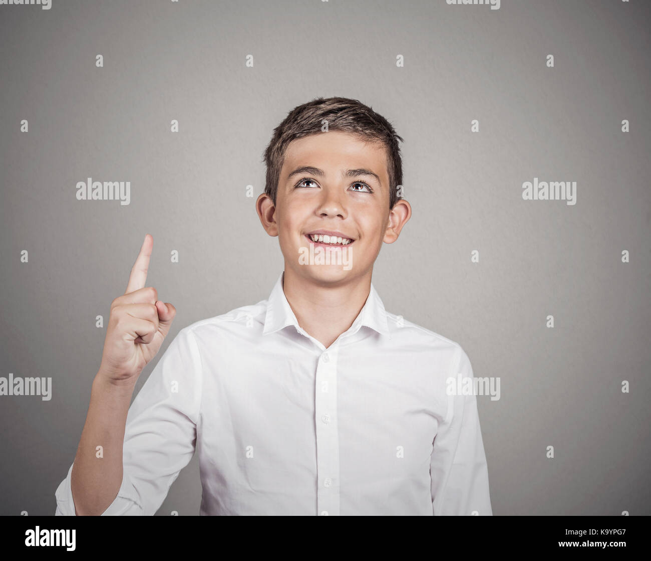 Boy looking, pointing up, has idea, solution, isolated grey wall ...