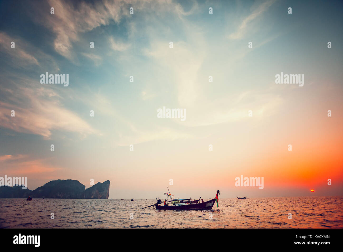 Traditional long boat and beautiful tropic sunset Stock Photo - Alamy