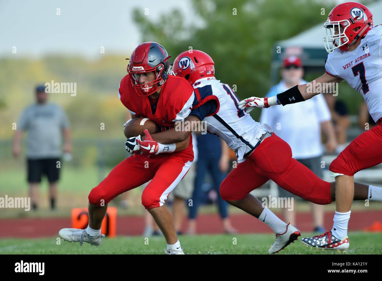 Wide out striving to hold on to a pass reception while being hit by an ...