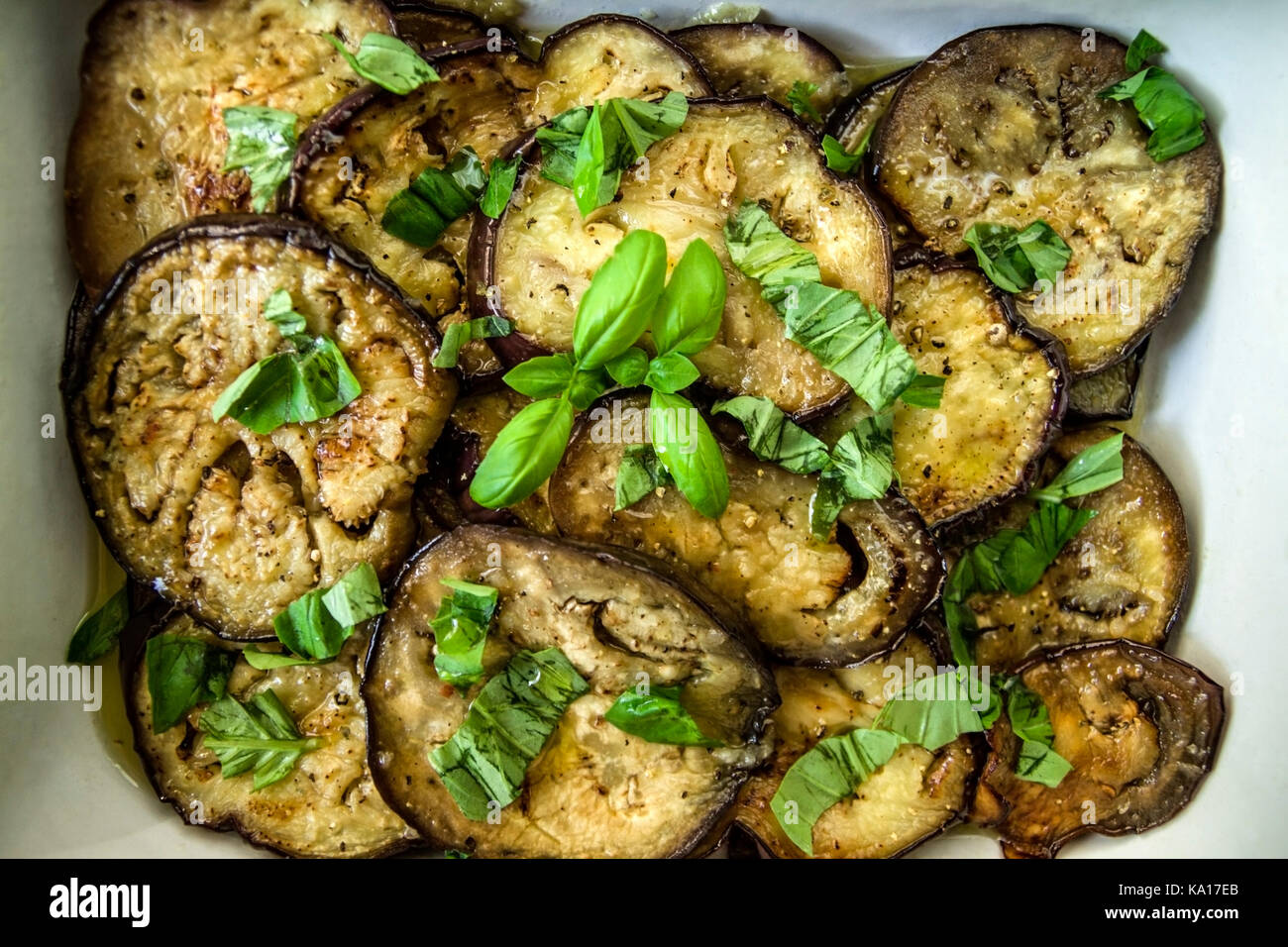 Fried and cooked aubergine with garlic basil in olive oil Stock Photo ...