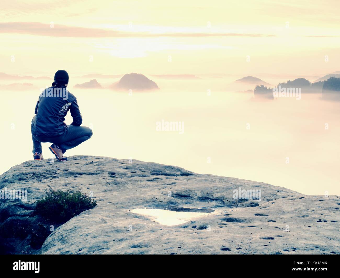 Man stands alone on the peak of rock. Hiker watching to autumn Sun at ...