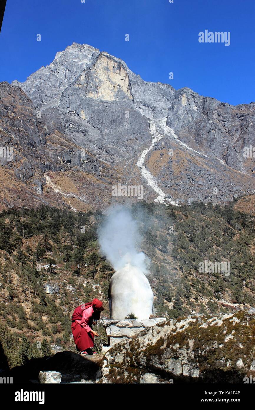 Monk starting a fire at the ceremonial oven. Khunde monastery ...