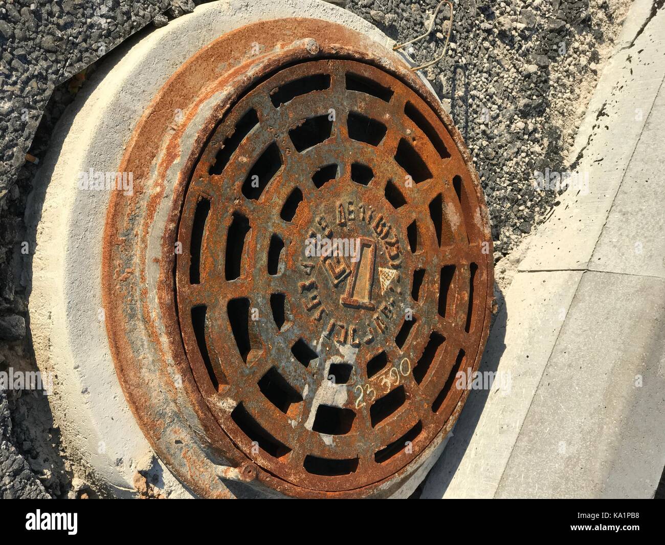 Rusty iron manhole set into asphalt road surfaces Stock Photo - Alamy
