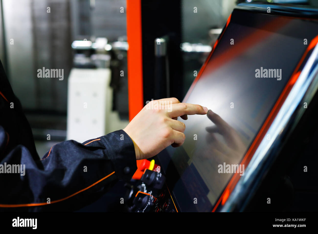 The operator adjusts modern CNC lathe machine using the touch screen ...