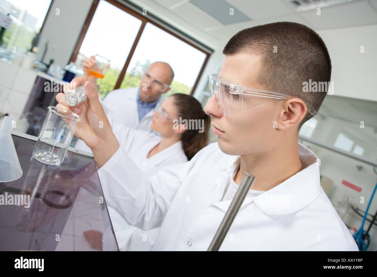 Student scientist pouring chemical into beaker Stock Photo - Alamy
