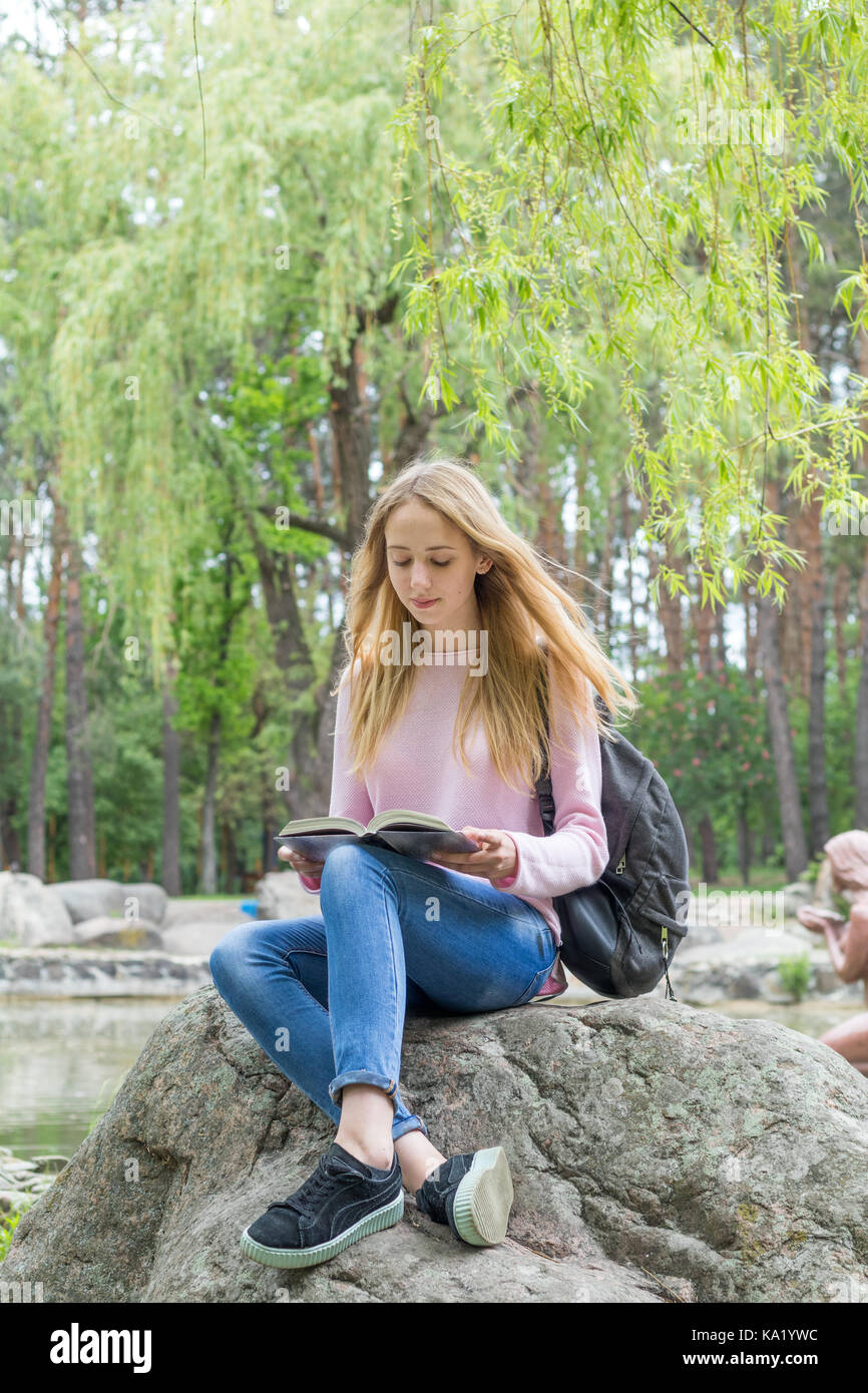 Cute Romantic Blond Teenage Girl Is Reading A Book Sitting Under The