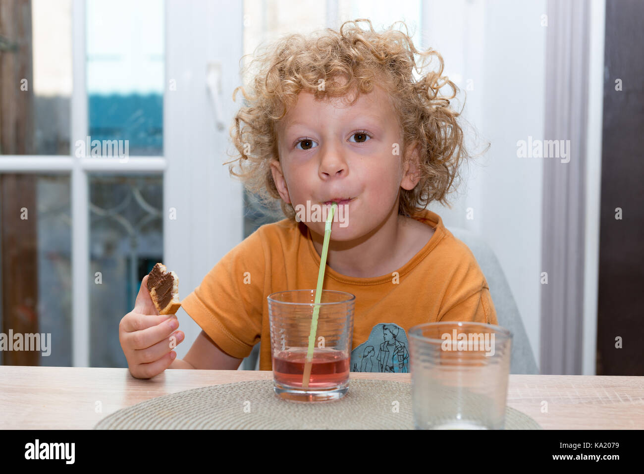 a cute little boy is drinking red juice using straw Stock Photo - Alamy