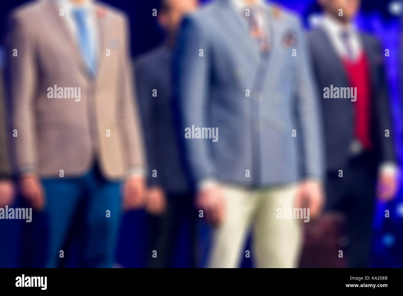 Blurry out of focus (defocus) Male models walk the runway in different ...