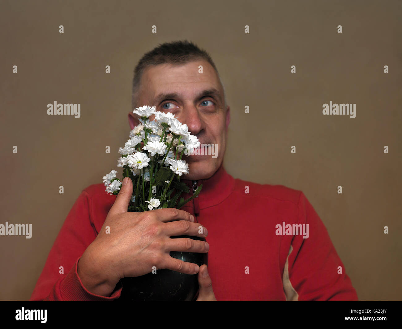 Funny looking man holding a vase with beautiful chrysanthemum, studio ...
