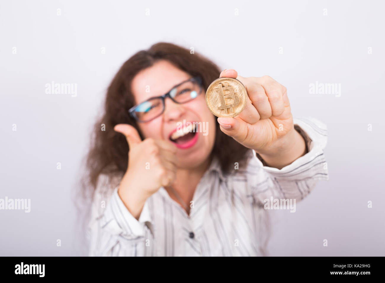 Laughing business woman showing Golden Bitcoin coin and thumbs up ...