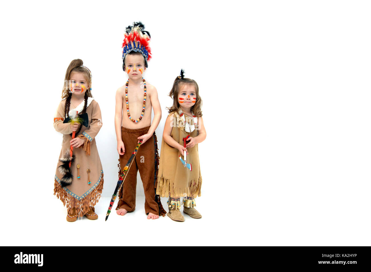 Three little indians, dressed in costumes and holding weapons, greet ...