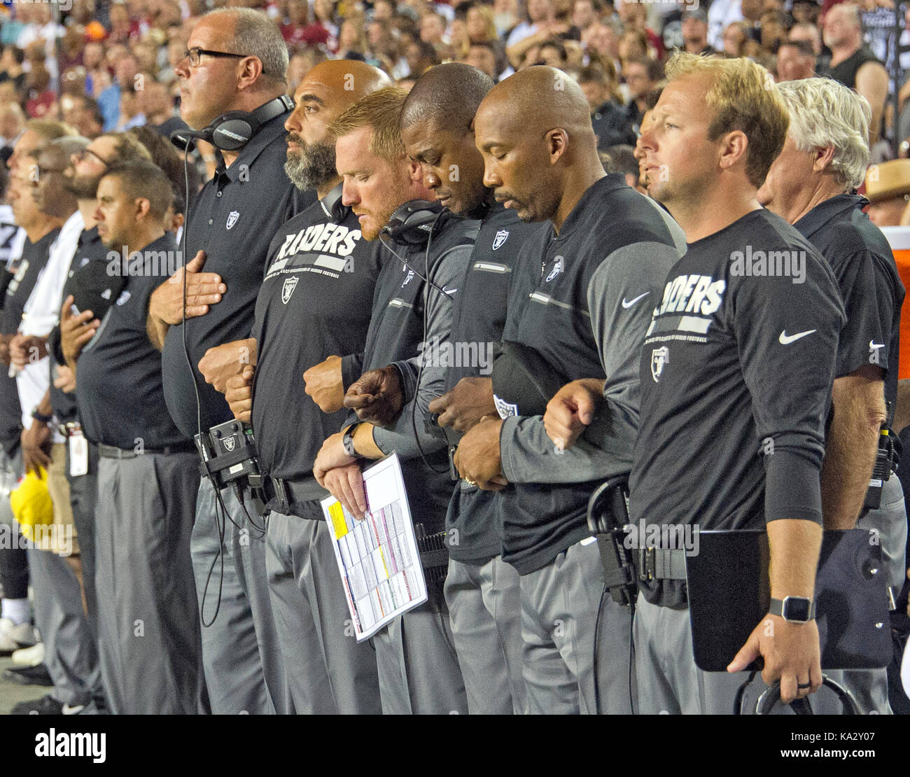 Oakland Raiders coaches stand with locked arms in solidarity as the ...