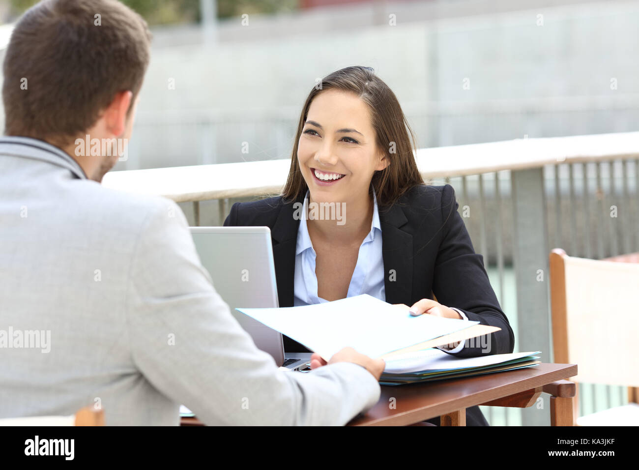 Two executives working sharing informs sitting in a bar terrace Stock ...