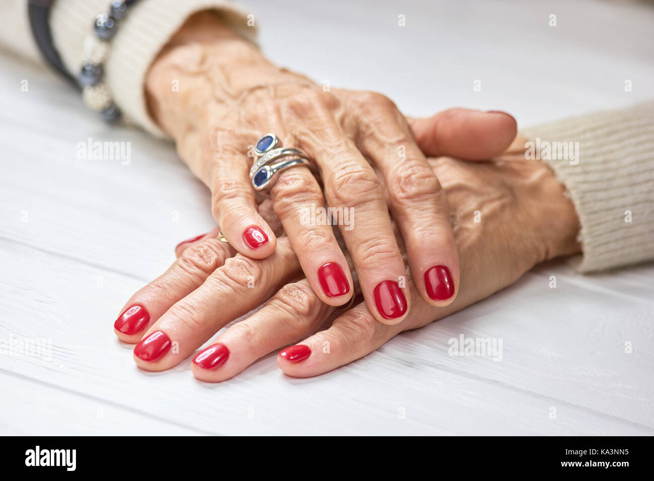 Woman manicured hands on table. Female aged hands with perfect red ...
