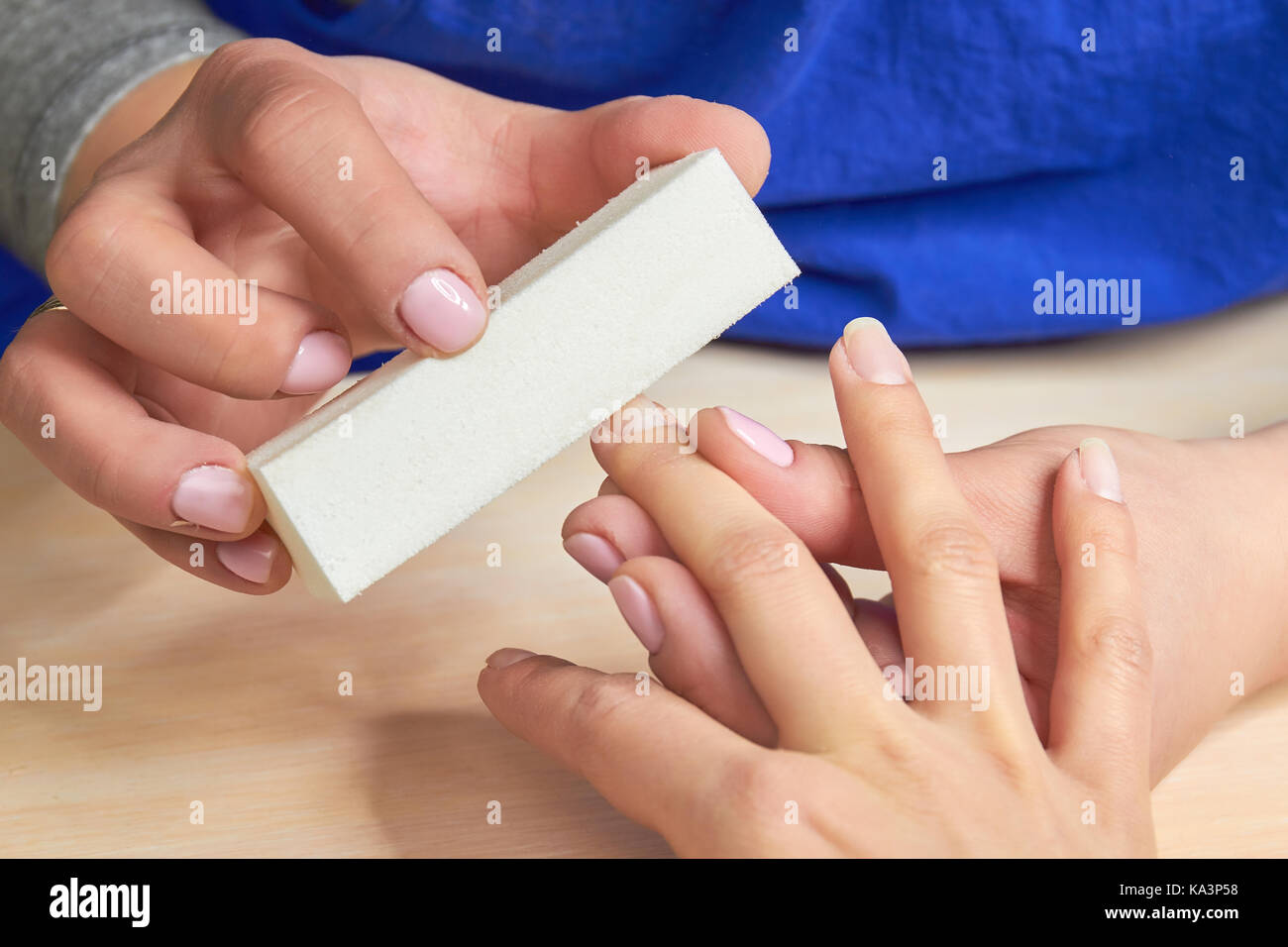 Manicurist polishing nails to client. Beautician filing nails for ...