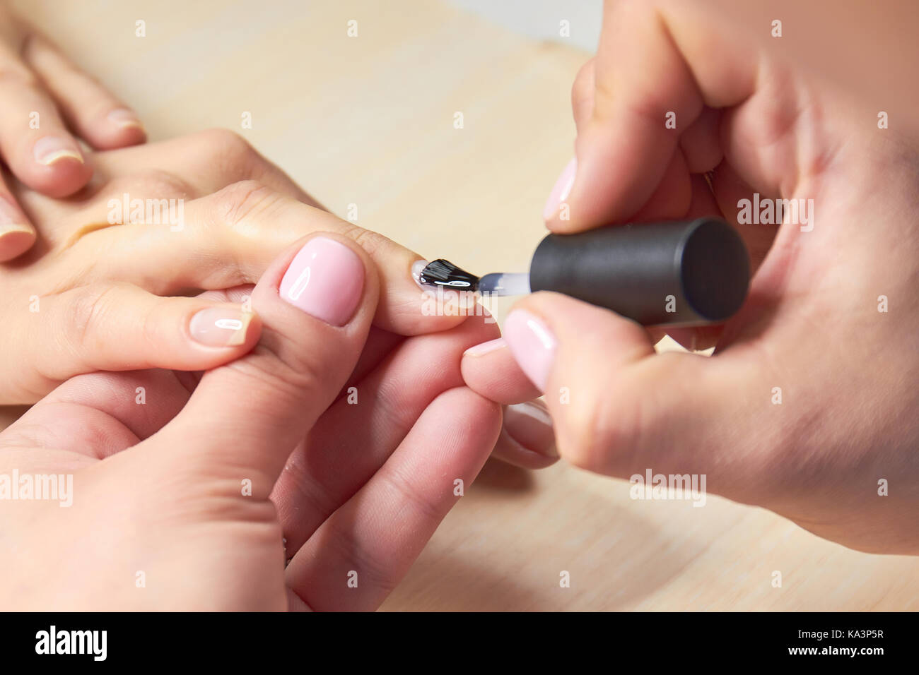 Beautician applying colorless varnish. Close up of woman applying nail ...