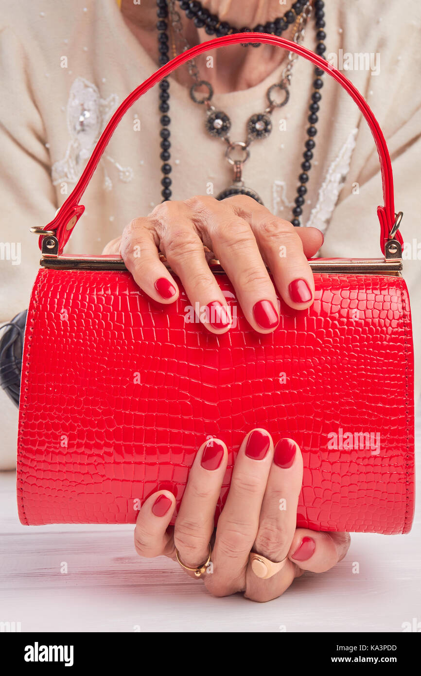 Beautiful red handbag in female hands. Woman hands with red manicure ...