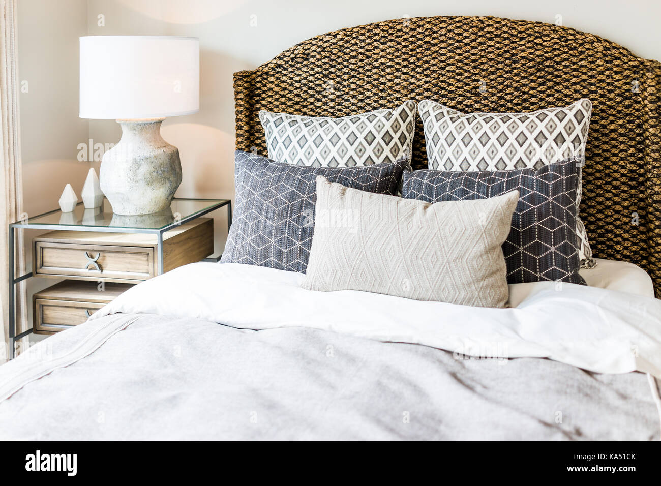 Closeup of new bed comforter with decorative pillows, headboard in ...