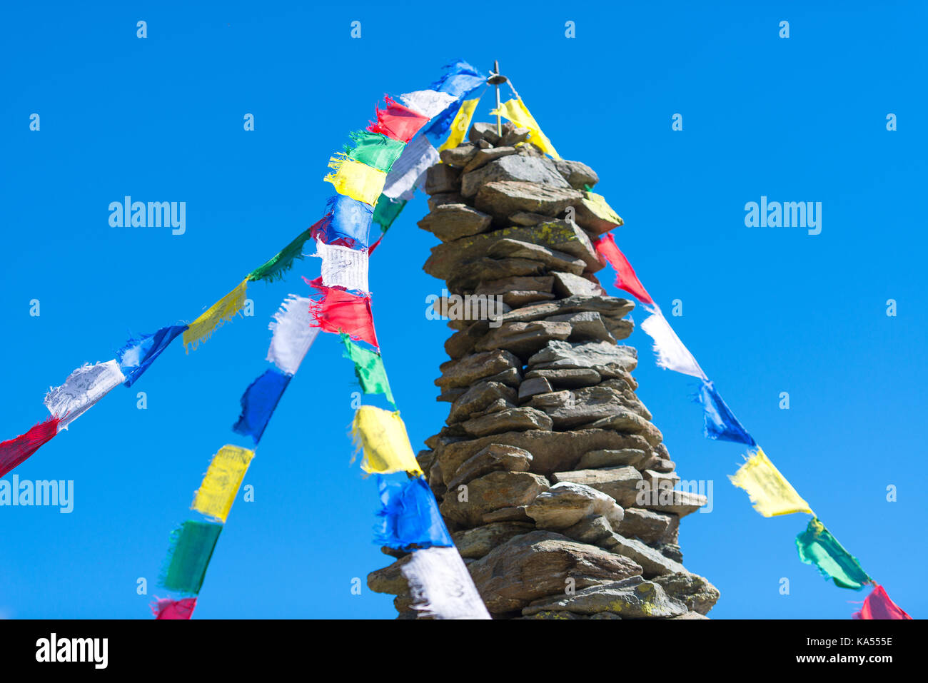 Colorful Tibetan Buddhist prayer flags hanging on a stone pile or tower ...