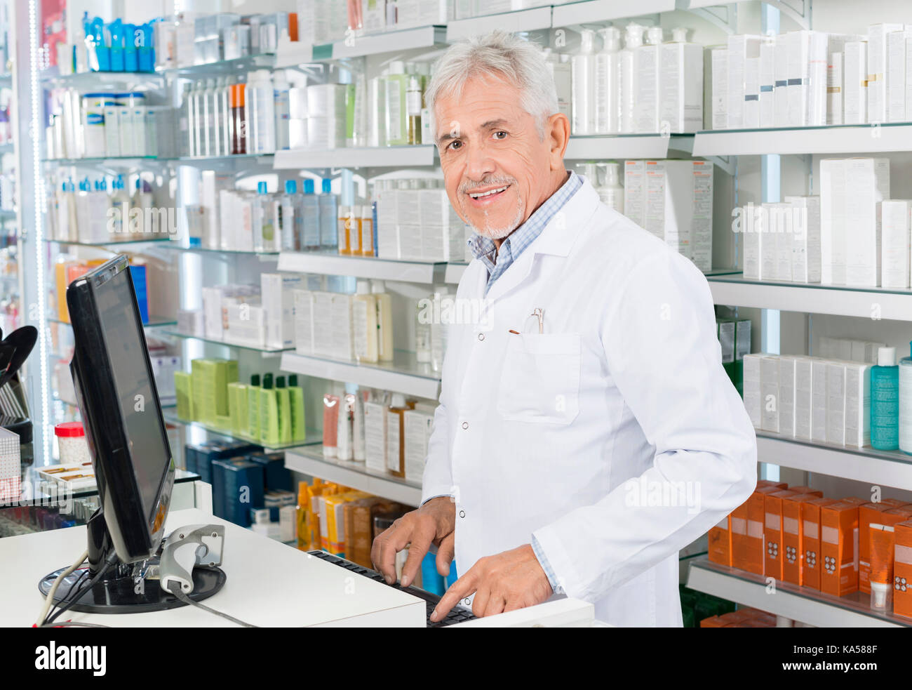 Senior Chemist Using Computer At Counter In Pharmacy Stock Photo - Alamy