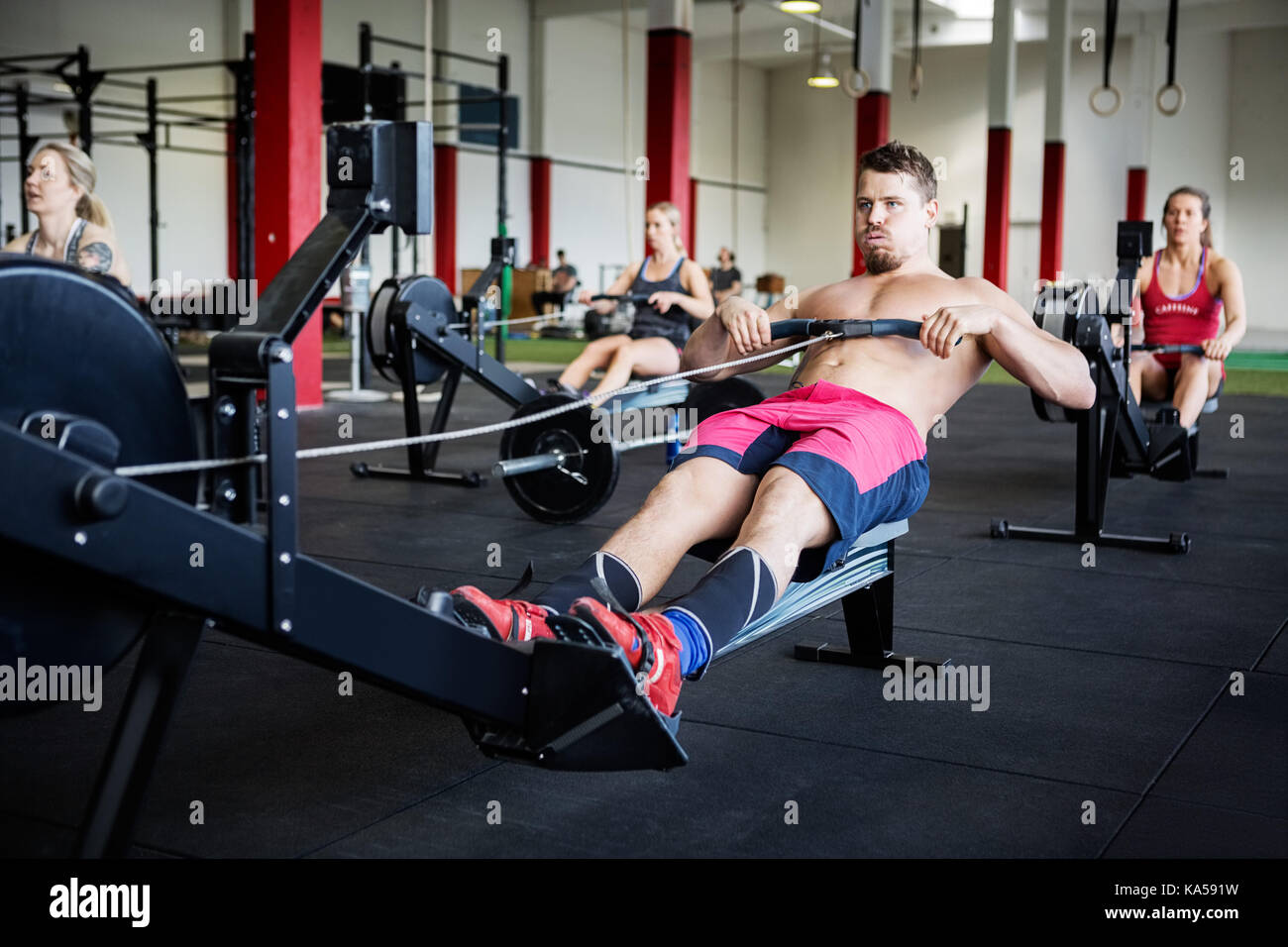 Muscular Man Using Rowing Machine In Gymnasium Stock Photo - Alamy