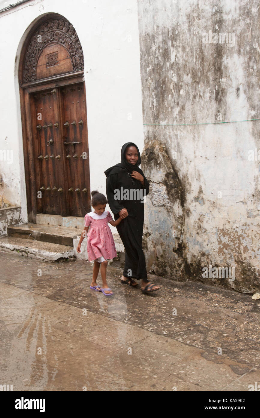 A mother and child walk through the flooded streets during a rain storm ...