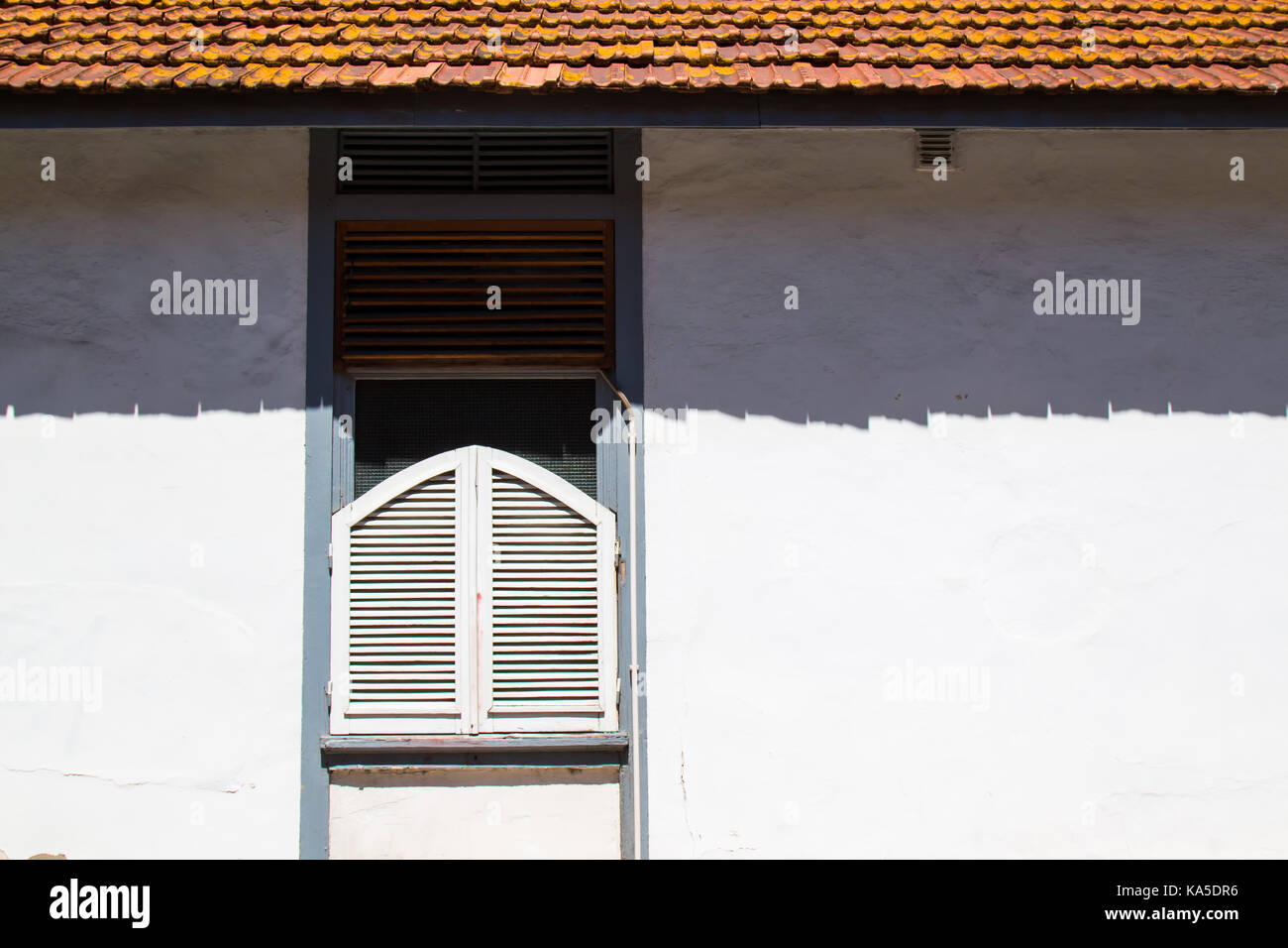 White facade of a house with a window with closed white shutter. Line ...