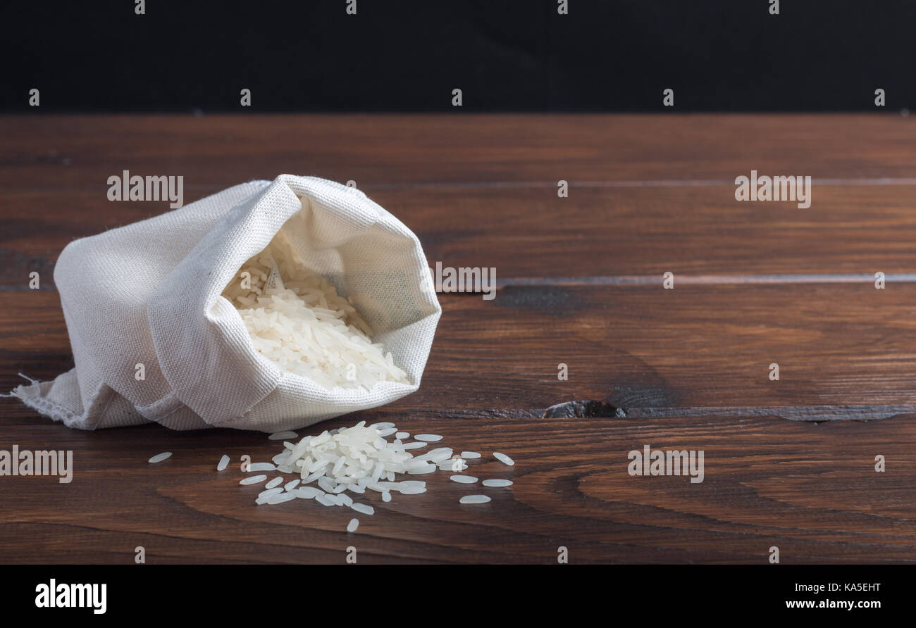 sac of rice on a wooden table with a dark background Stock Photo - Alamy