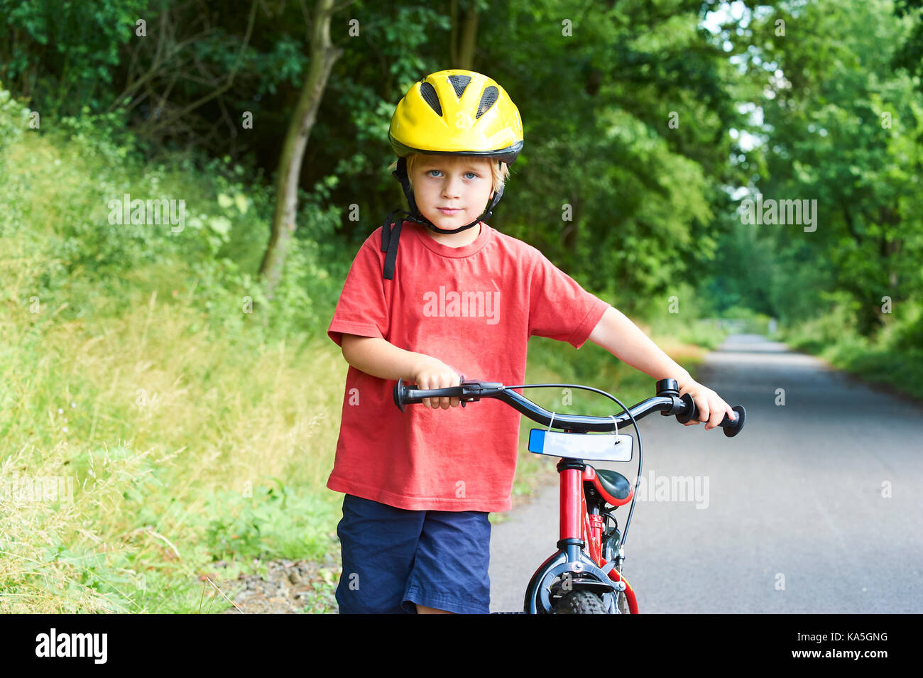 Young boy riding bicycle on a summer day at asphalt road. Bicycle path ...