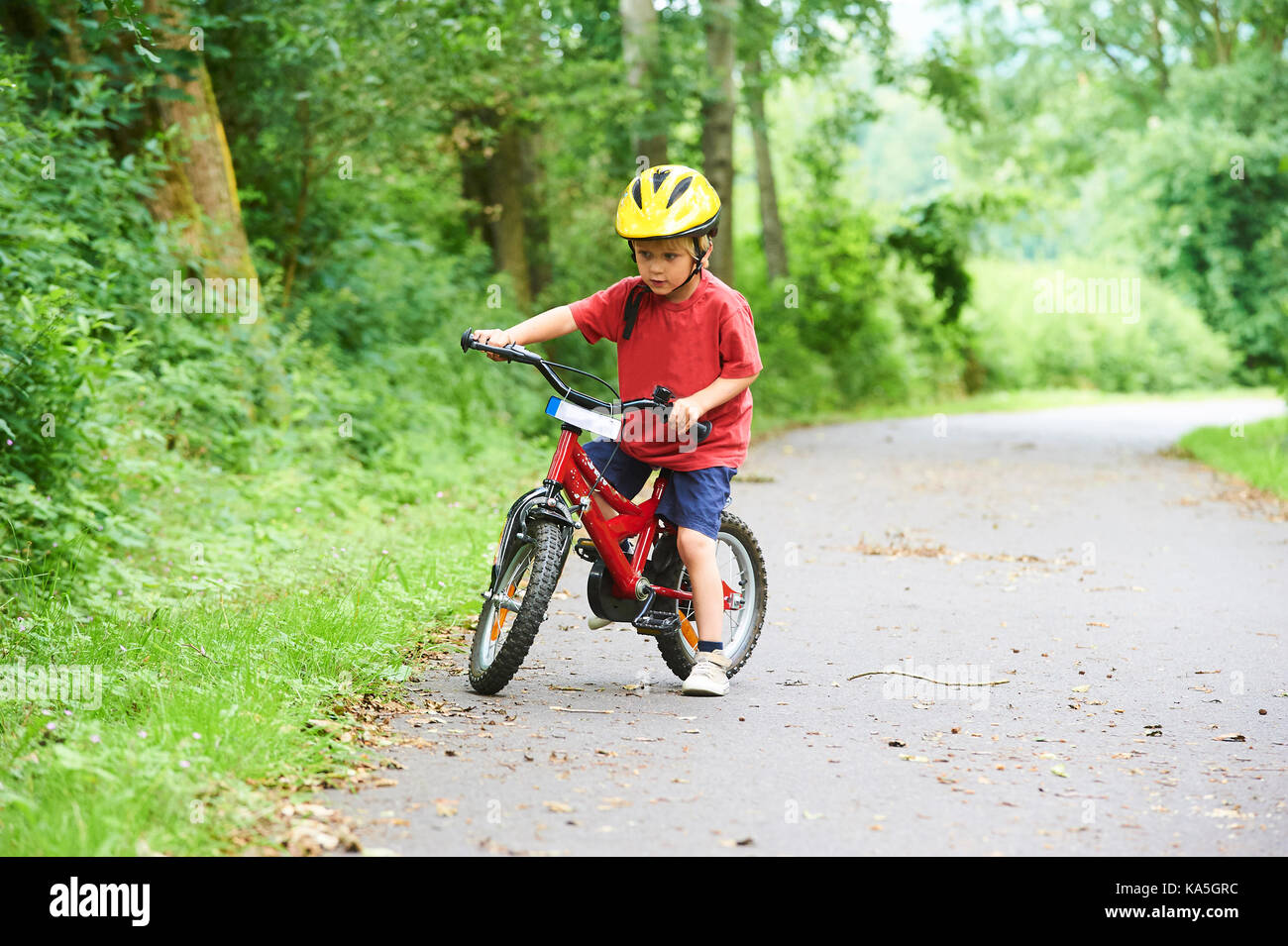 Young boy riding bicycle on a summer day at asphalt road. Bicycle path ...