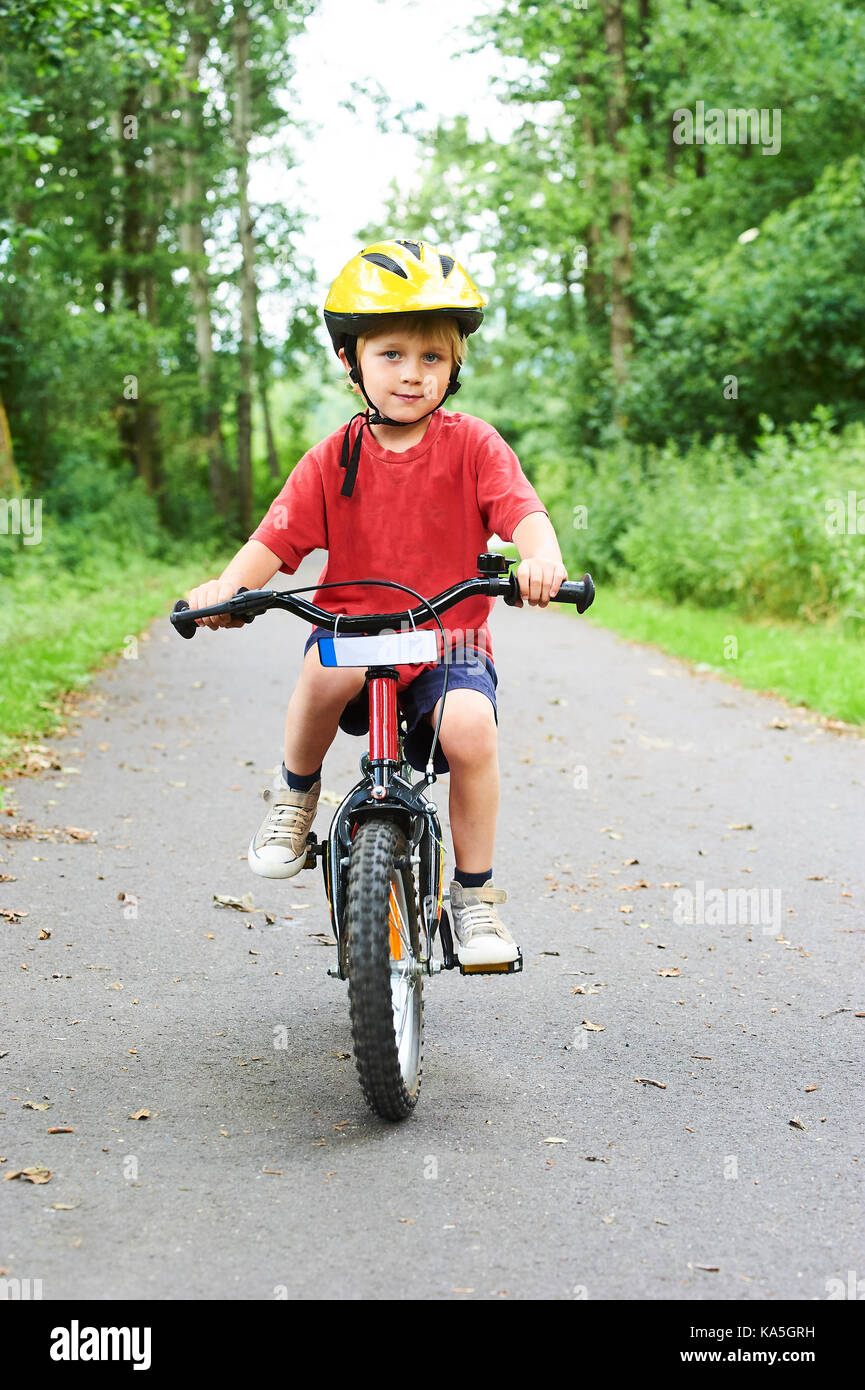 Young boy riding bicycle on a summer day at asphalt road. Bicycle path ...
