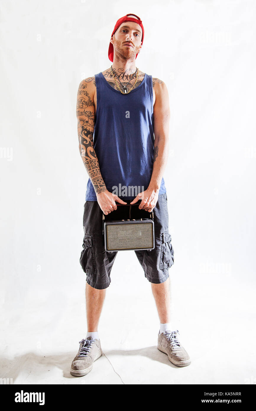 tattooed rap singer posing in studio with an amplified radio on a white ...