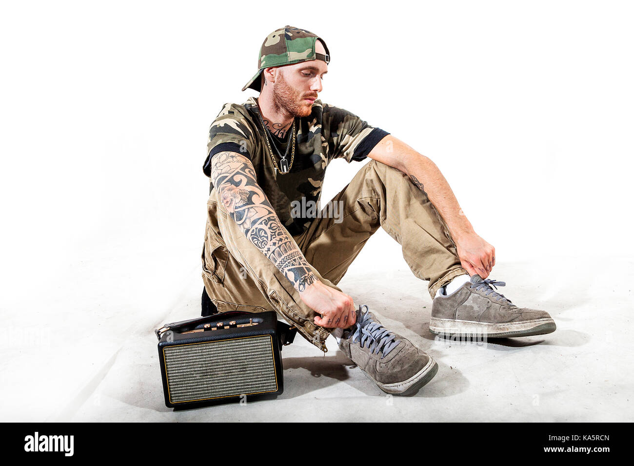 sitting tattooed rap singer posing in studio with an amplified radio on ...