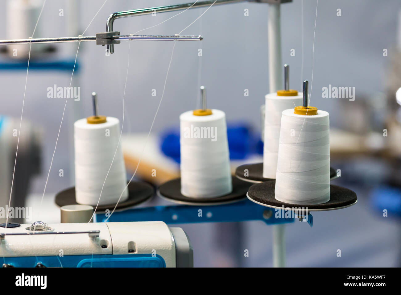Spools of white threads on sewing machine, closeup. Cloth factory ...
