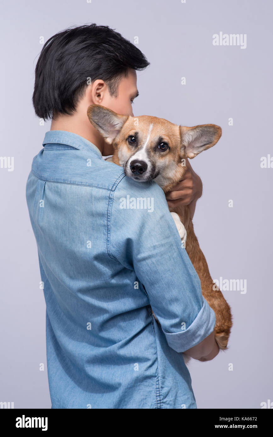 A man snuggling and hugging his dog, close friendship loving in studio ...
