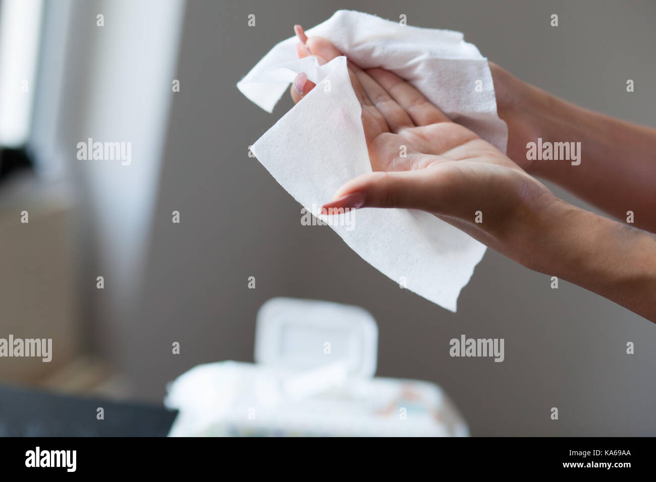Woman with long nails clean hands with wet wipes, blurred package in ...