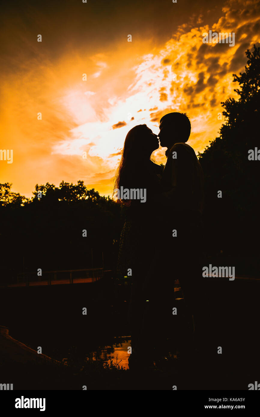 Beautiful young couple on the sunset background Stock Photo - Alamy