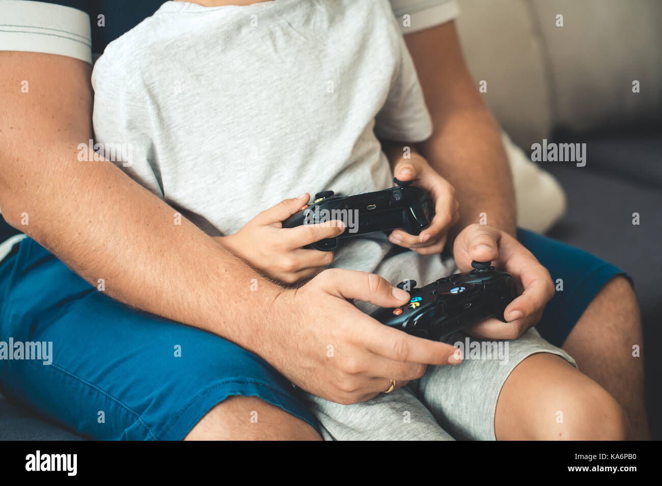 Father and son holding a joystick controllers while playing a video ...