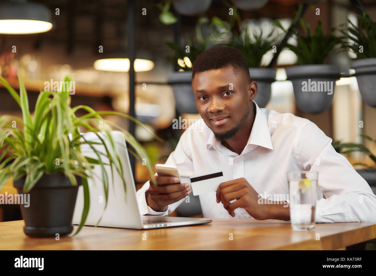 African man sending money with smart phone and laptop Stock Photo - Alamy