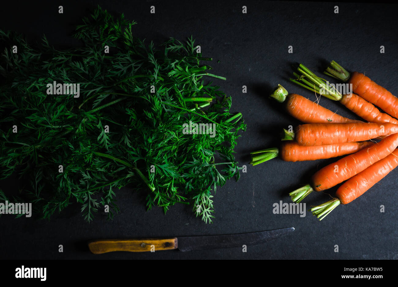Carrots, sliced tops and a knife on a gray stone horizontal Stock Photo ...