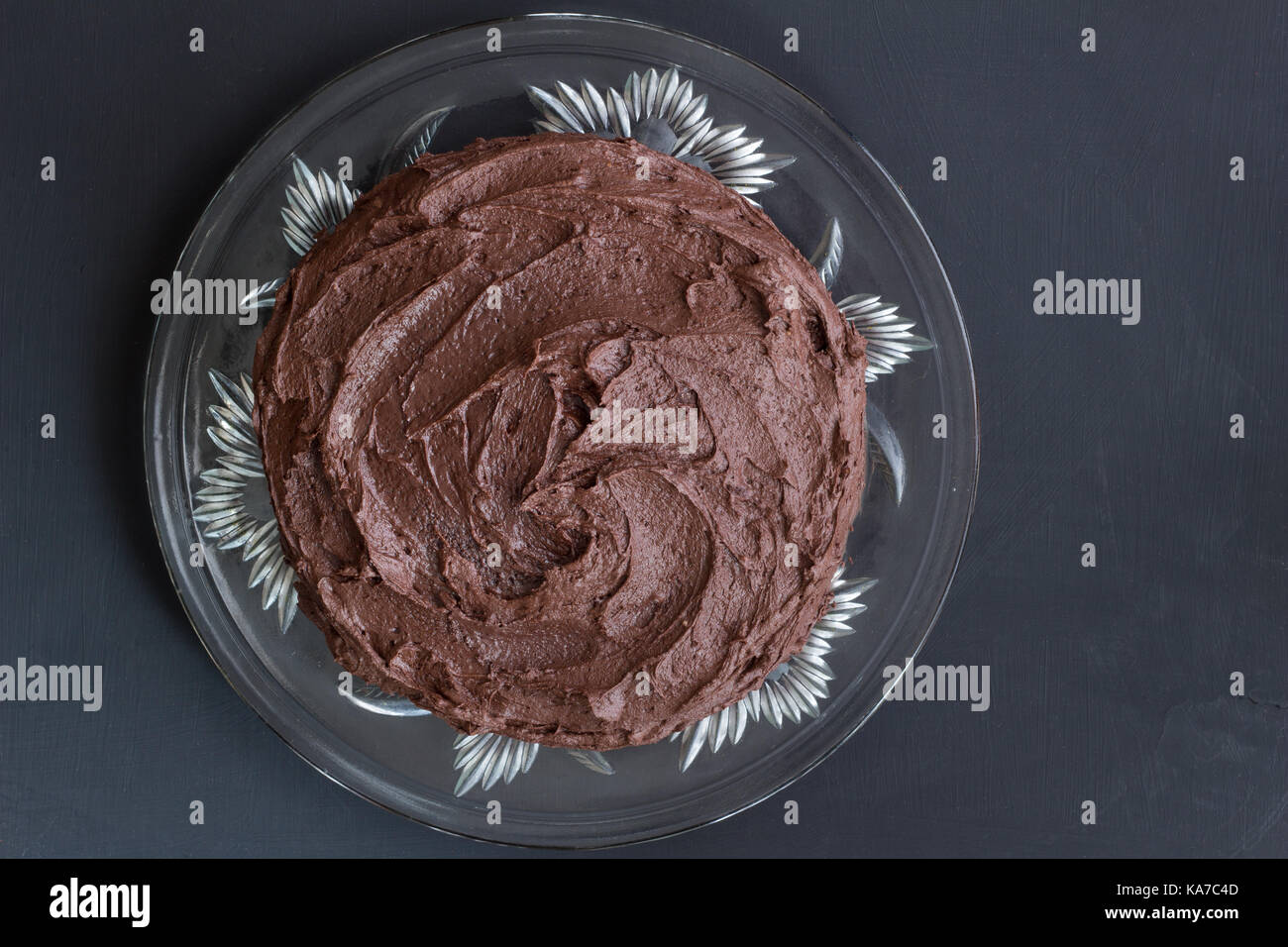 Top view of rich chocolate cake on glass plate on black background ...