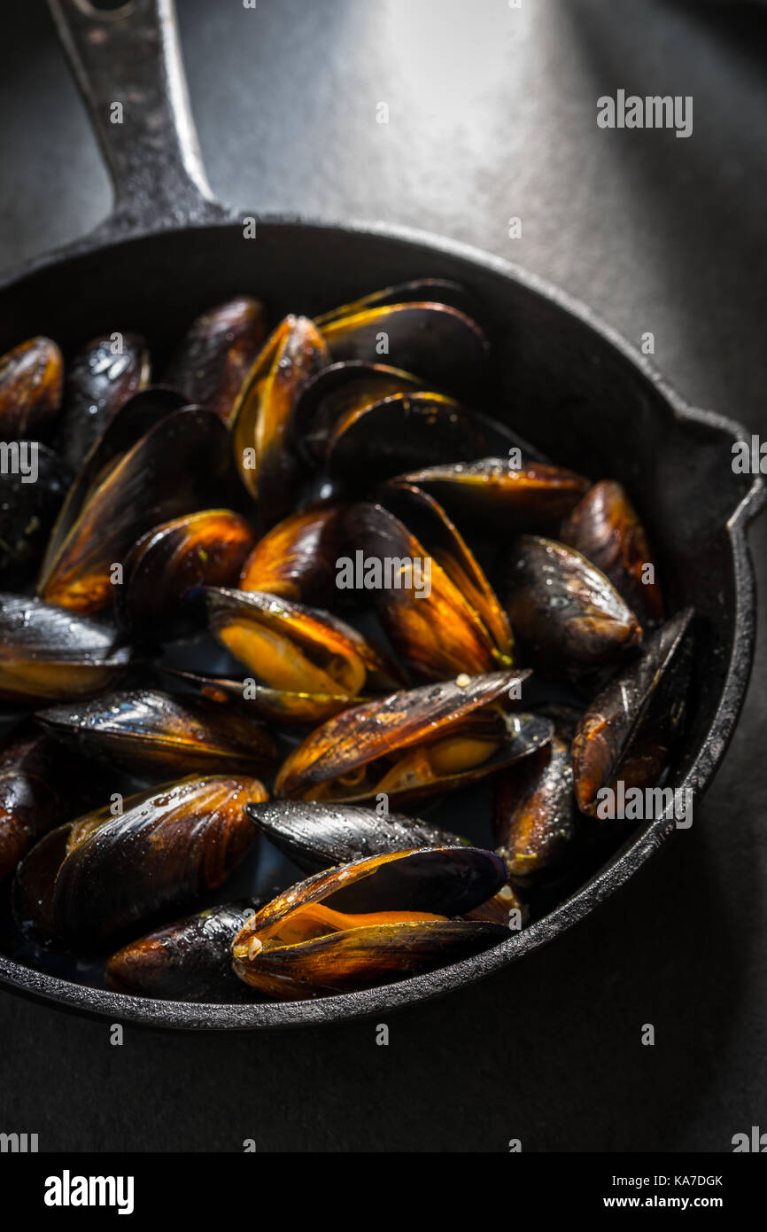 Mussels on a cast-iron frying pan on a gray background close-up ...