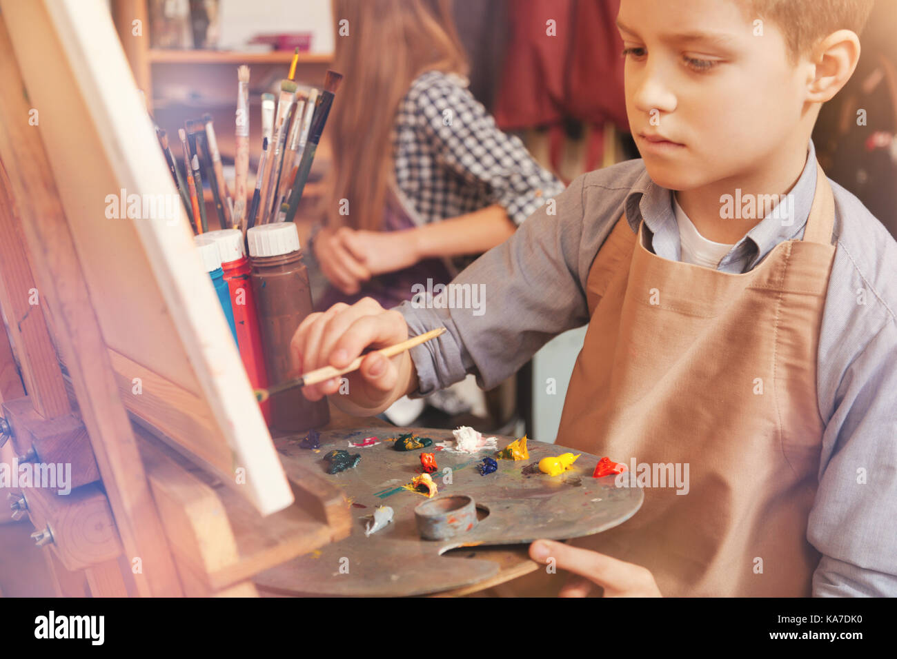 Serious young boy painting on art canvas Stock Photo - Alamy